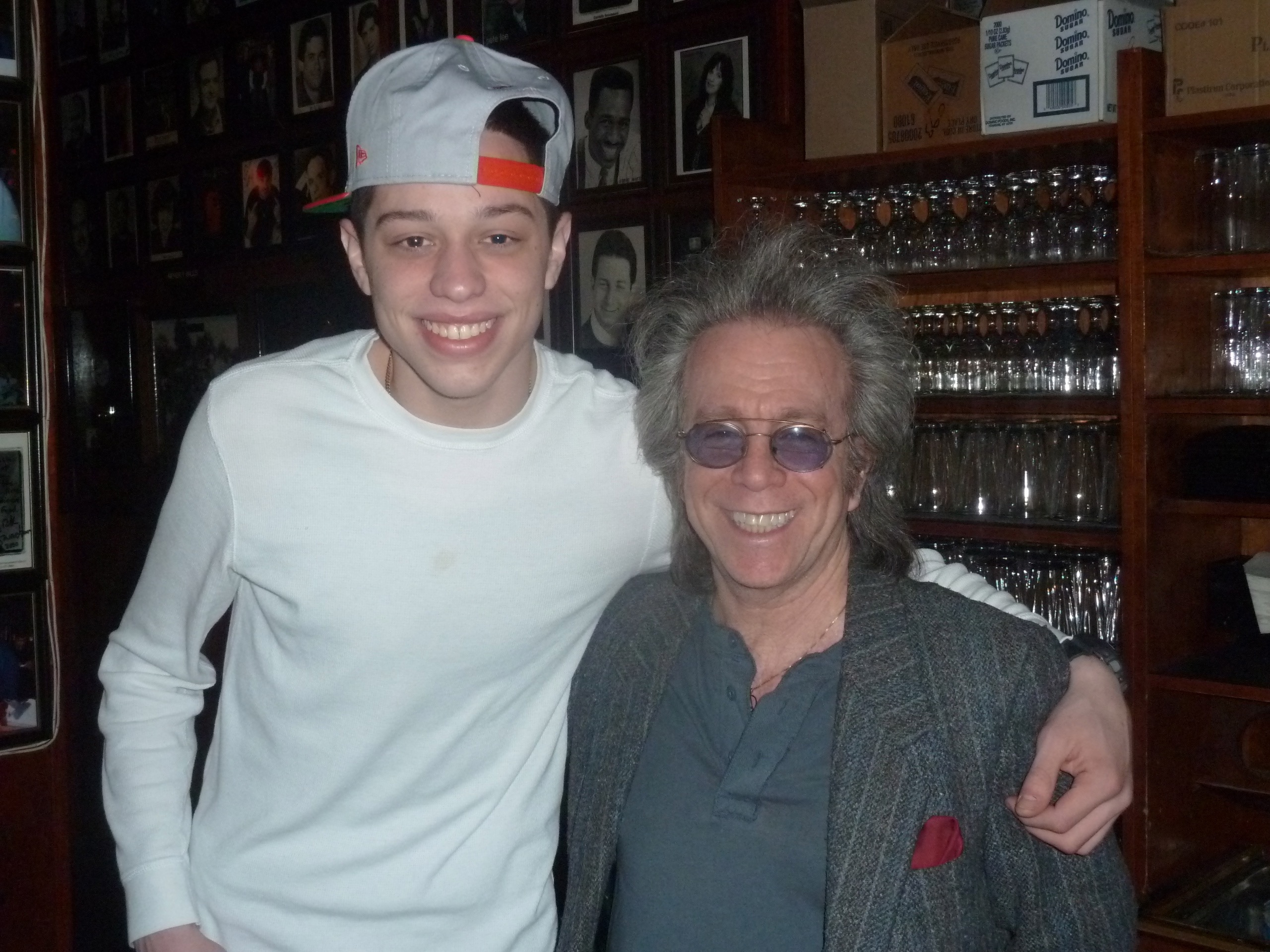 Two men smiling, one wearing a backward cap and the other sunglasses ...