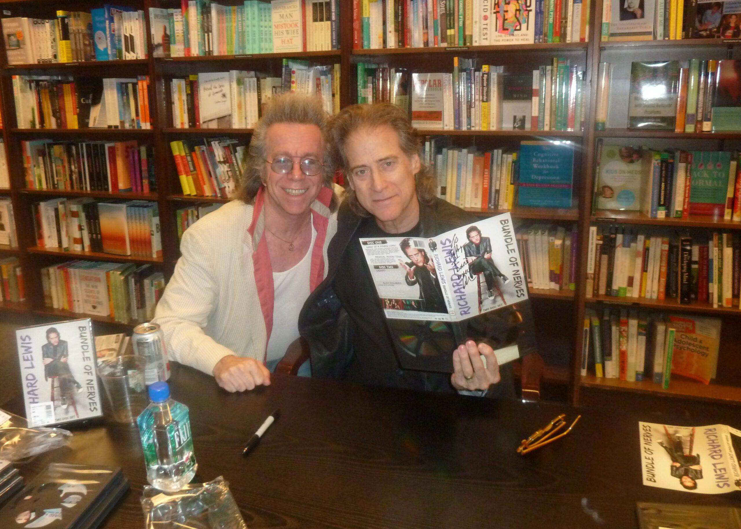 Two men posing with a book in a bookstore. - Jeffrey Gurian